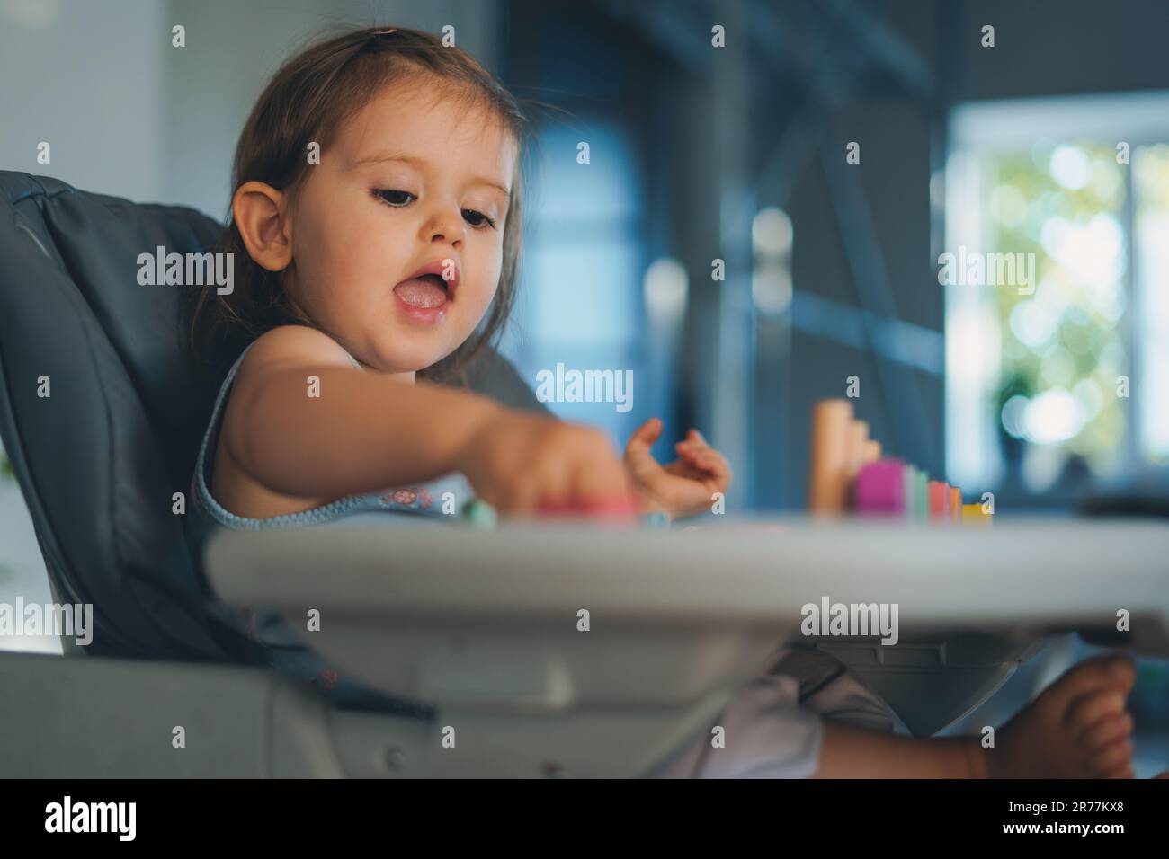 Child sitting on a high-chair collecting a puzzle of numbers, learning ...