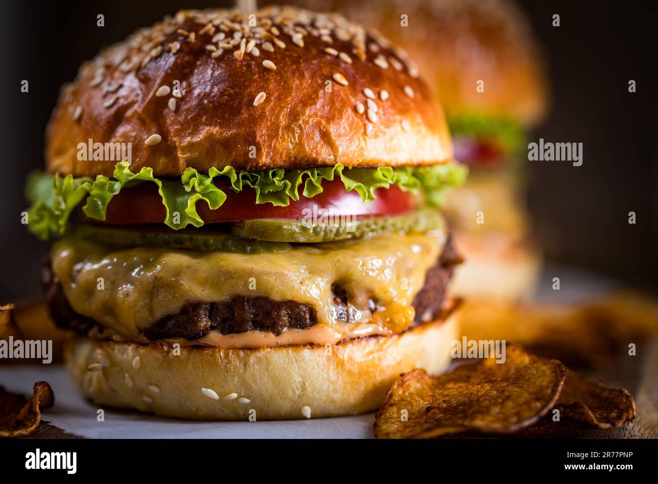 Tasty cheeseburger with lettuce, cheddar cheese, tomato and pickles ...