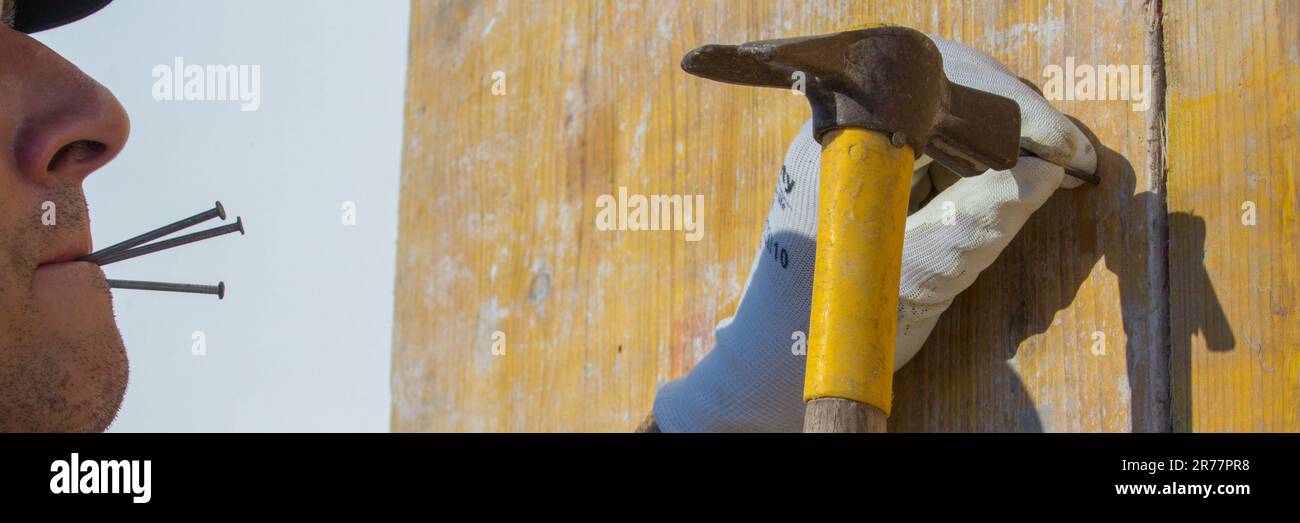 Image of a bricklayer nailing boards with a hammer, holding nails ...