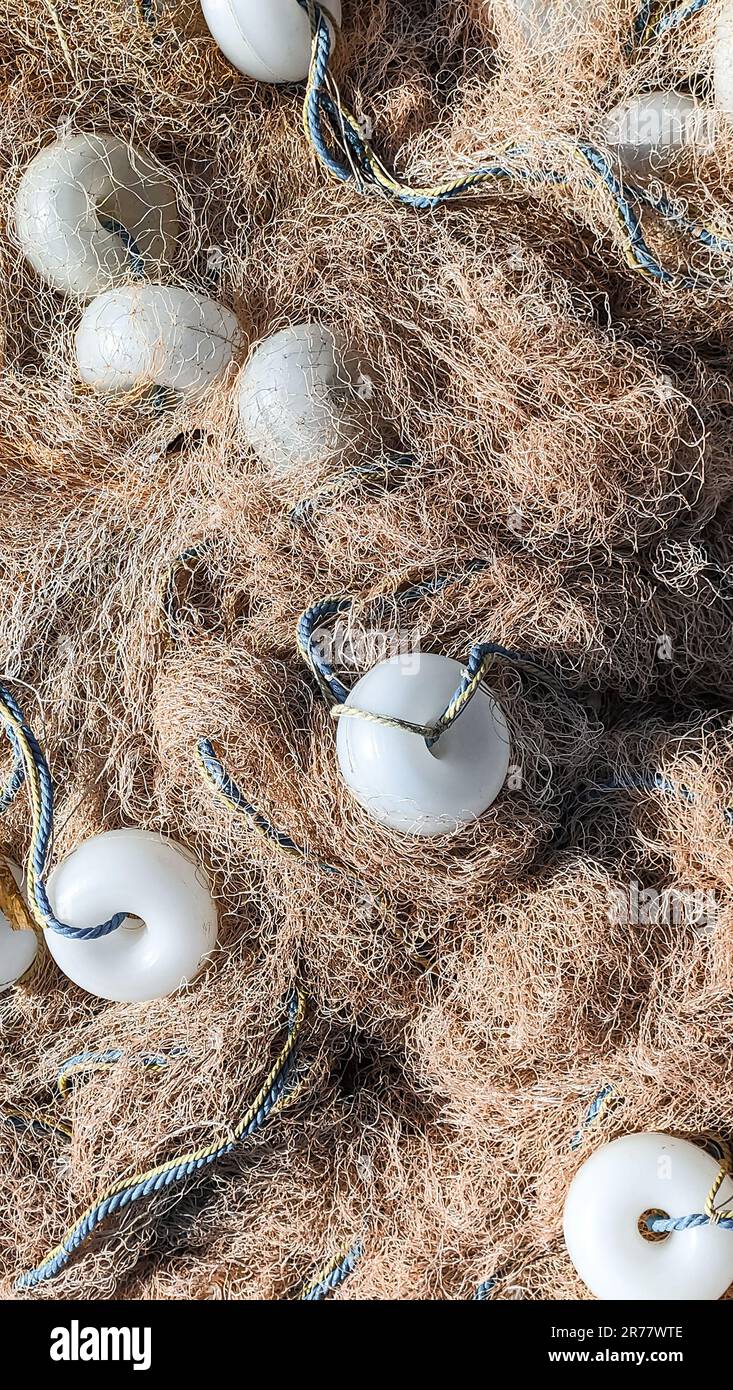 Fishing net with white floats and ropes lies on ground, top view ...