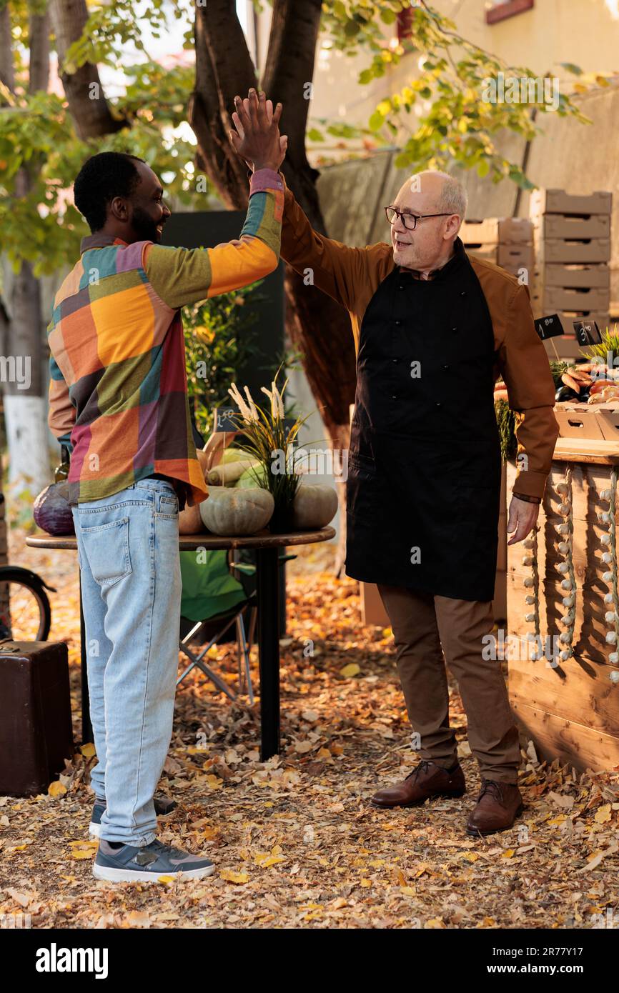 Positive small business owner greeting man with highfive, enjoying ...