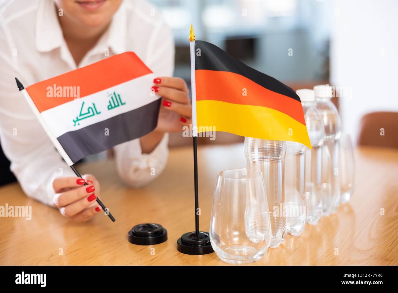 Female secretary places flags of the Iraq and Germany flag on the table ...