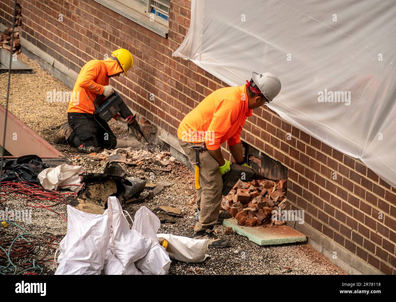 Workers perform city-mandated facade repair on the exterior of an ...