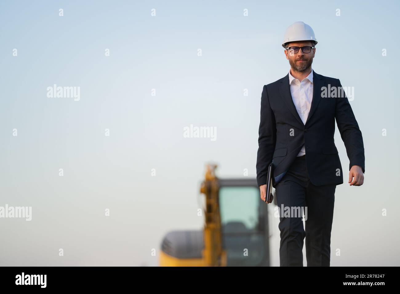 Construction owner near excavator. Confident construction owner in ...