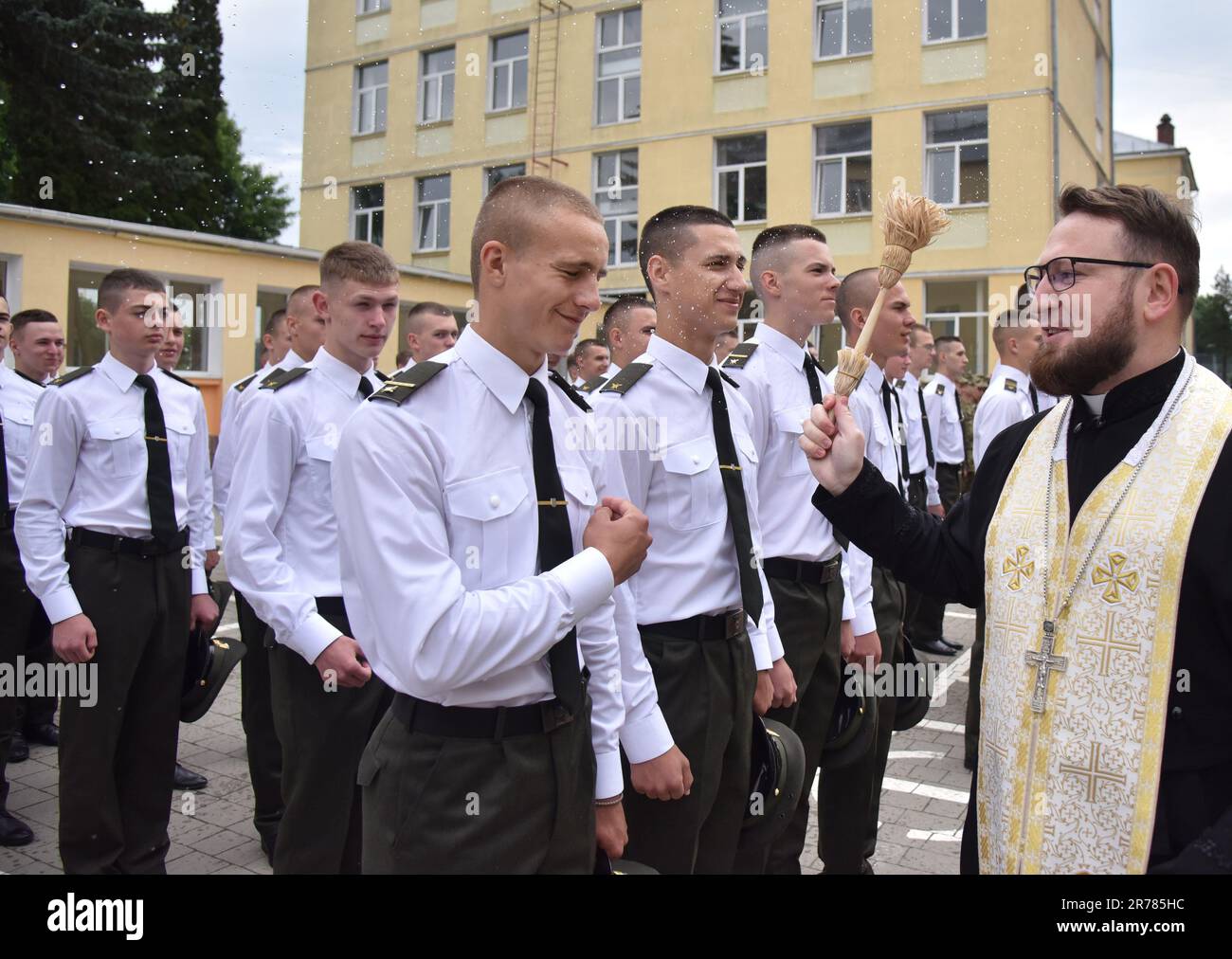 A priest sprinkles cadets with holy water during the graduation ...