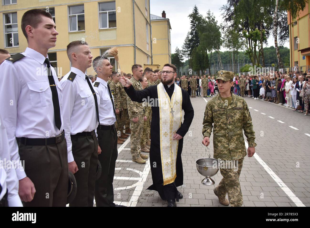 A priest sprinkles cadets with holy water during the graduation ...