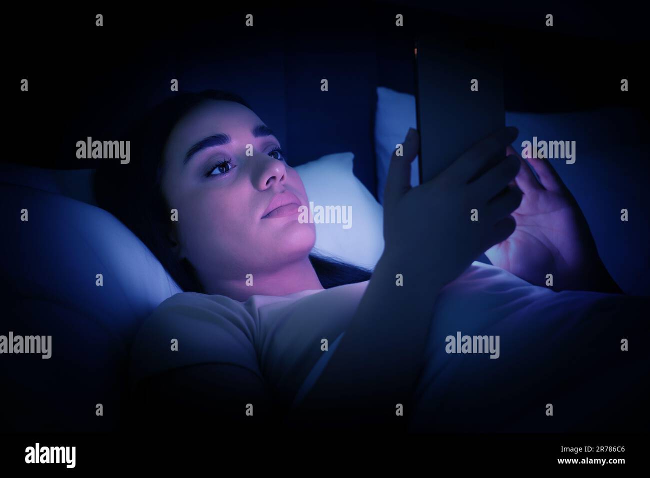 Internet addiction. Woman using smartphone on bed at night. Toned in ...
