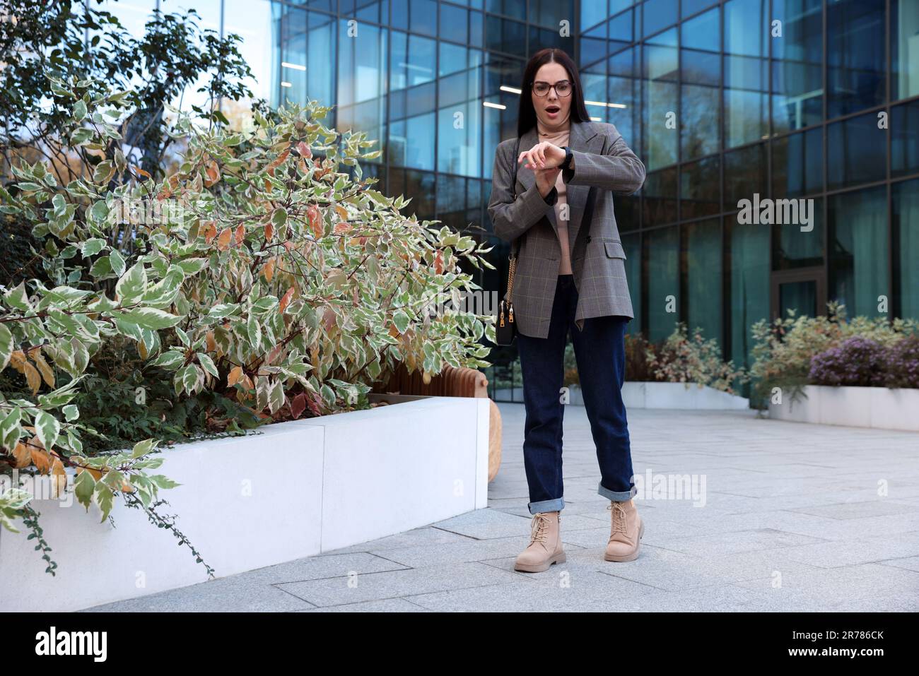 Emotional woman checking time on watch outdoors. Being late concept ...