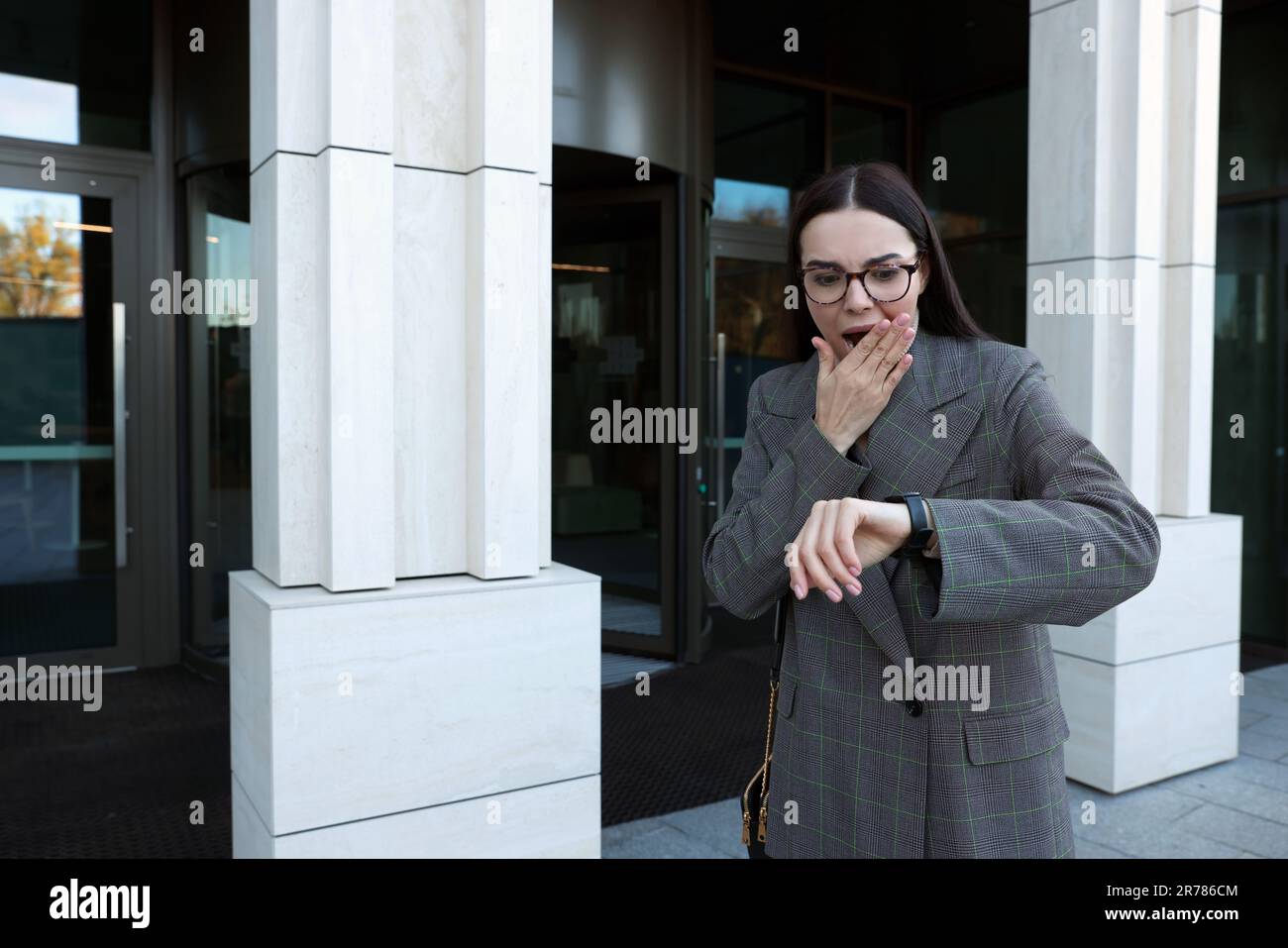 Emotional woman checking time on watch outdoors. Being late concept ...