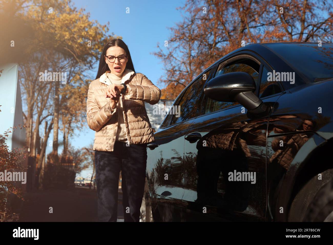 Emotional woman checking time on watch near car. Being late concept ...