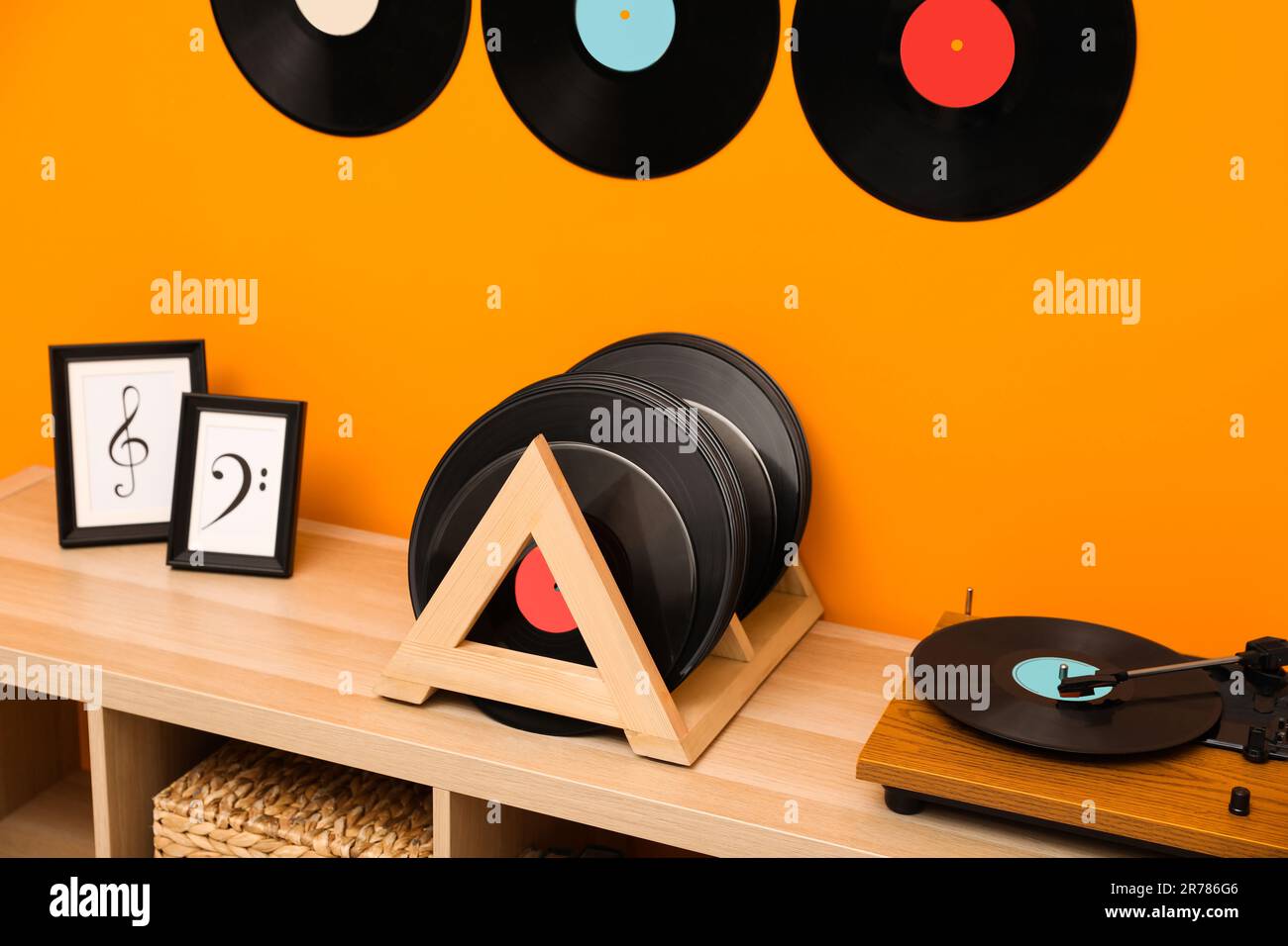 Vinyl records and player on wooden cabinet near orange wall Stock Photo ...