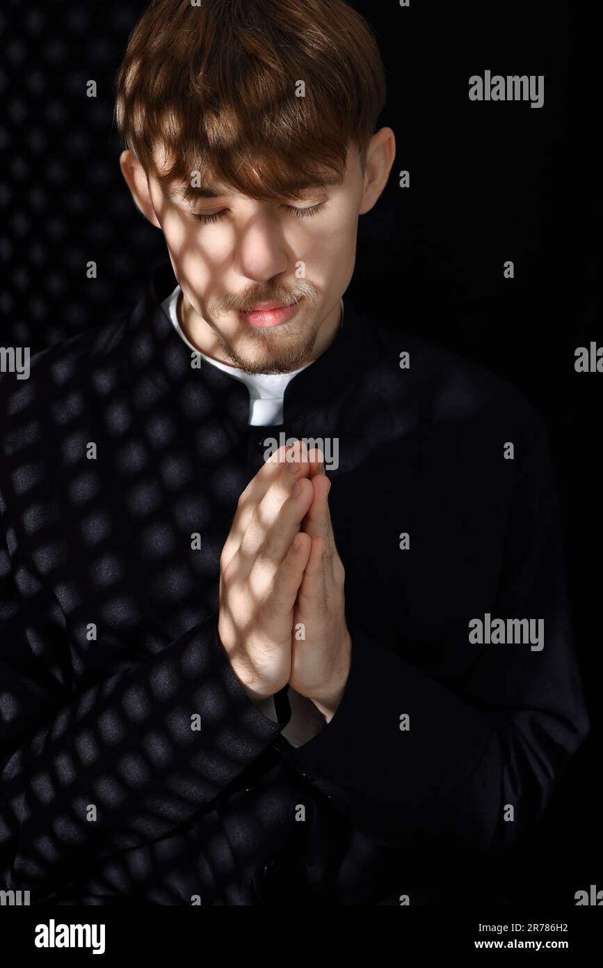 Catholic priest in cassock praying in confessional Stock Photo - Alamy