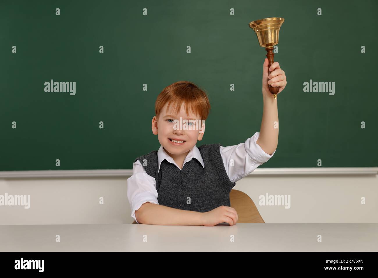 Cute little boy ringing school bell in classroom Stock Photo - Alamy