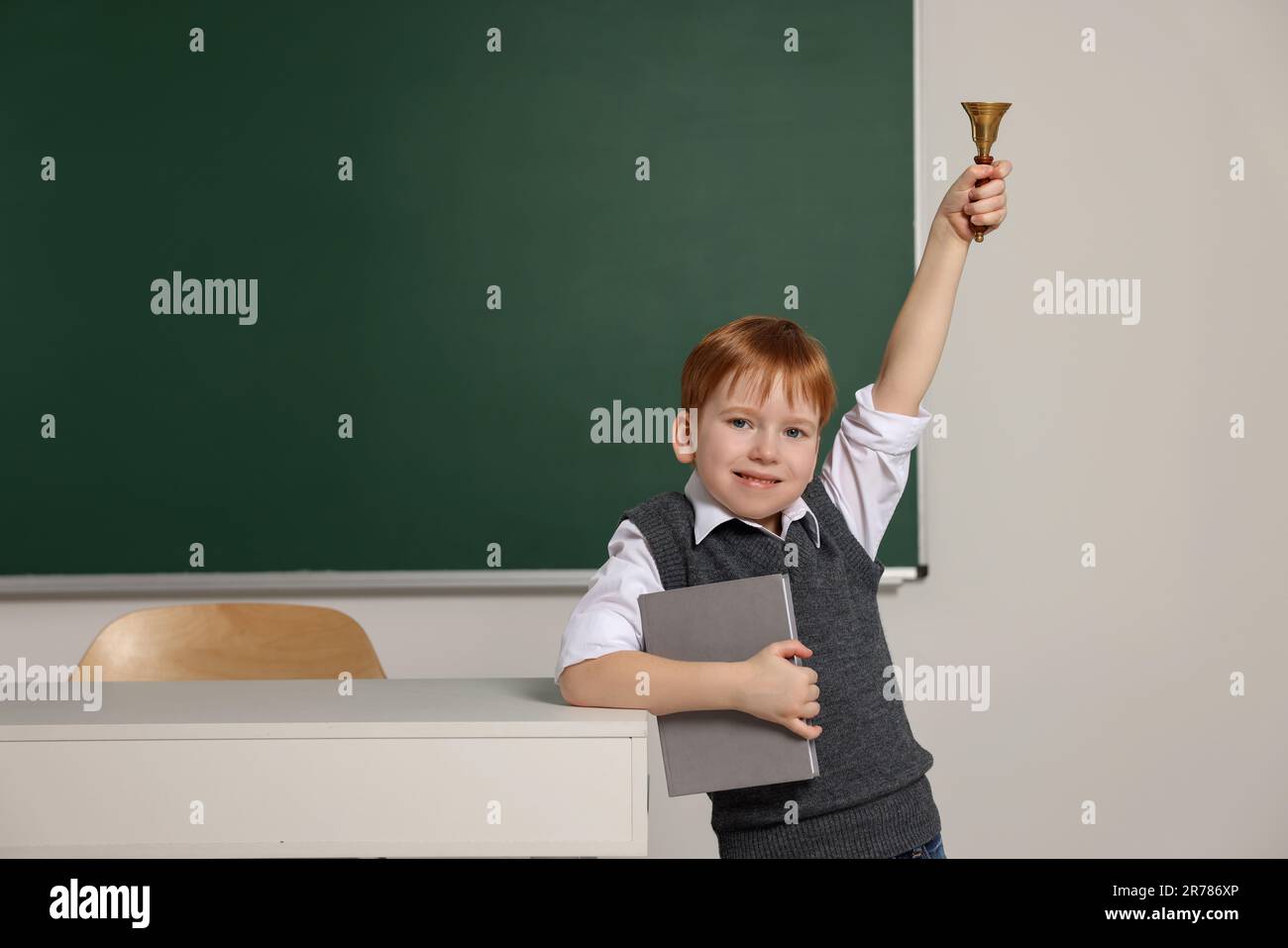 Cute little boy ringing school bell in classroom, space for text Stock ...