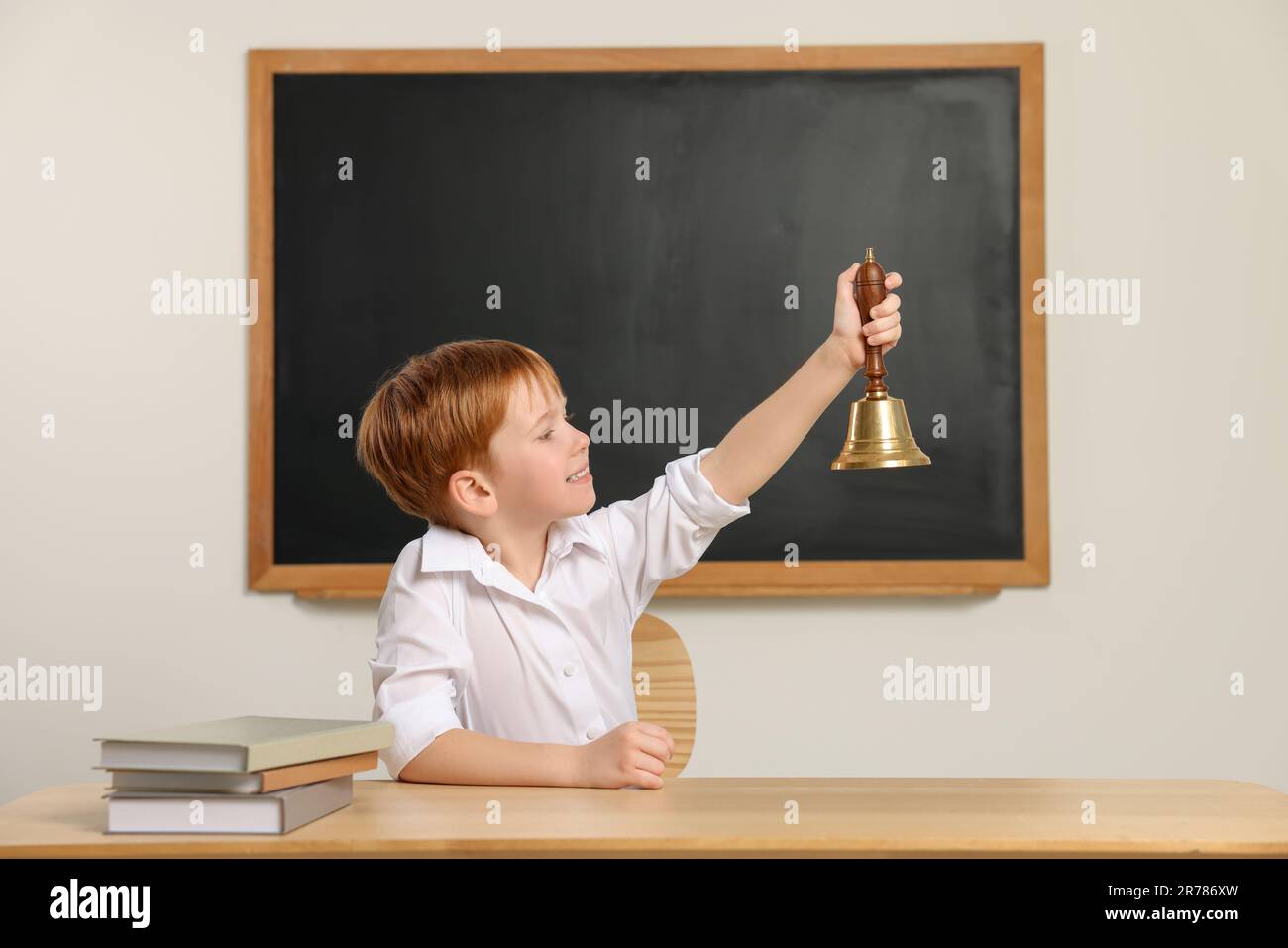 Cute little boy ringing school bell in classroom Stock Photo - Alamy