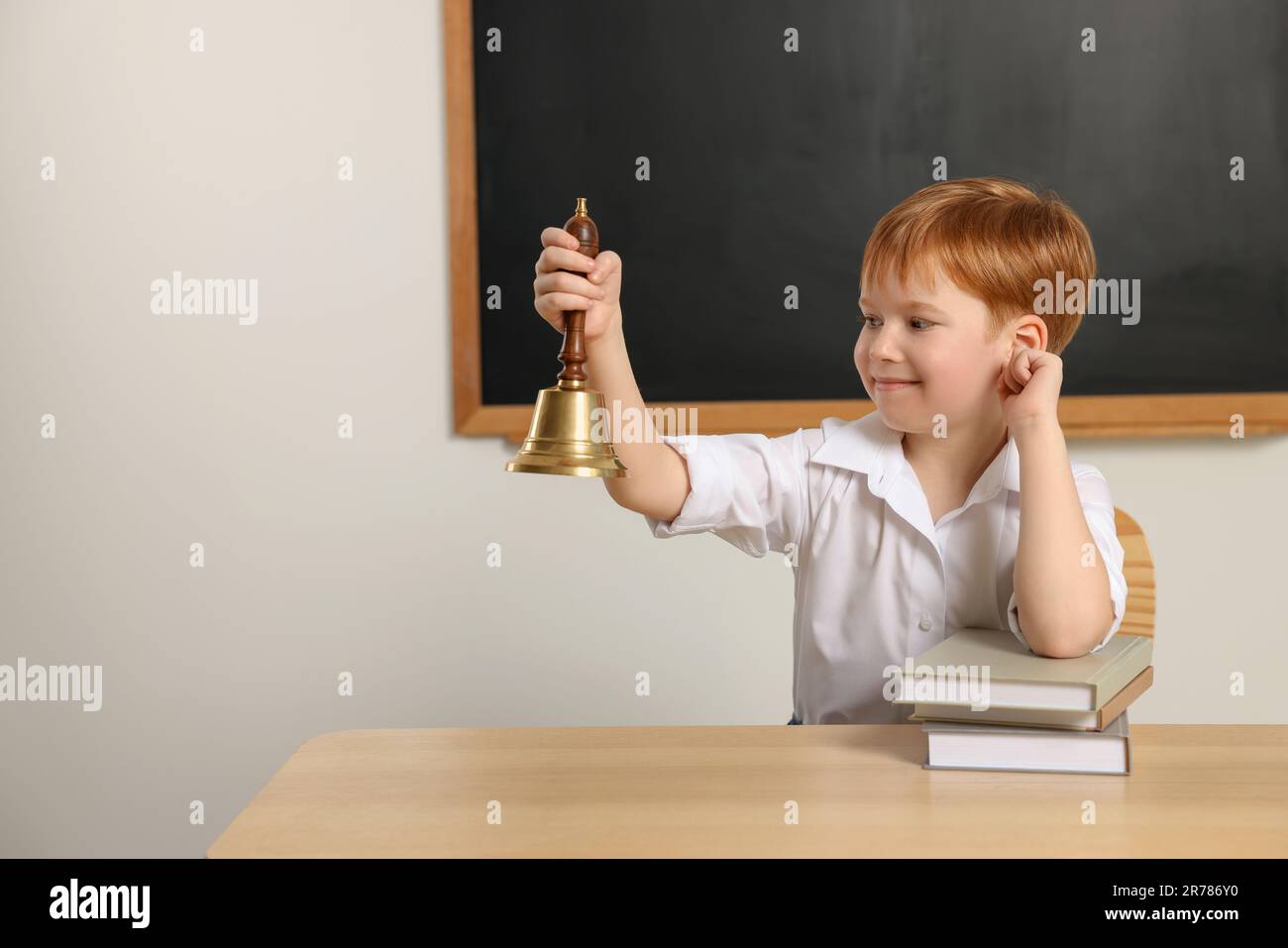 Cute little boy ringing school bell in classroom, space for text Stock ...