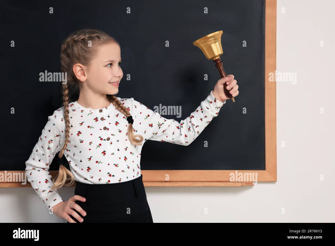 Pupil with school bell near black chalkboard in classroom Stock Photo ...