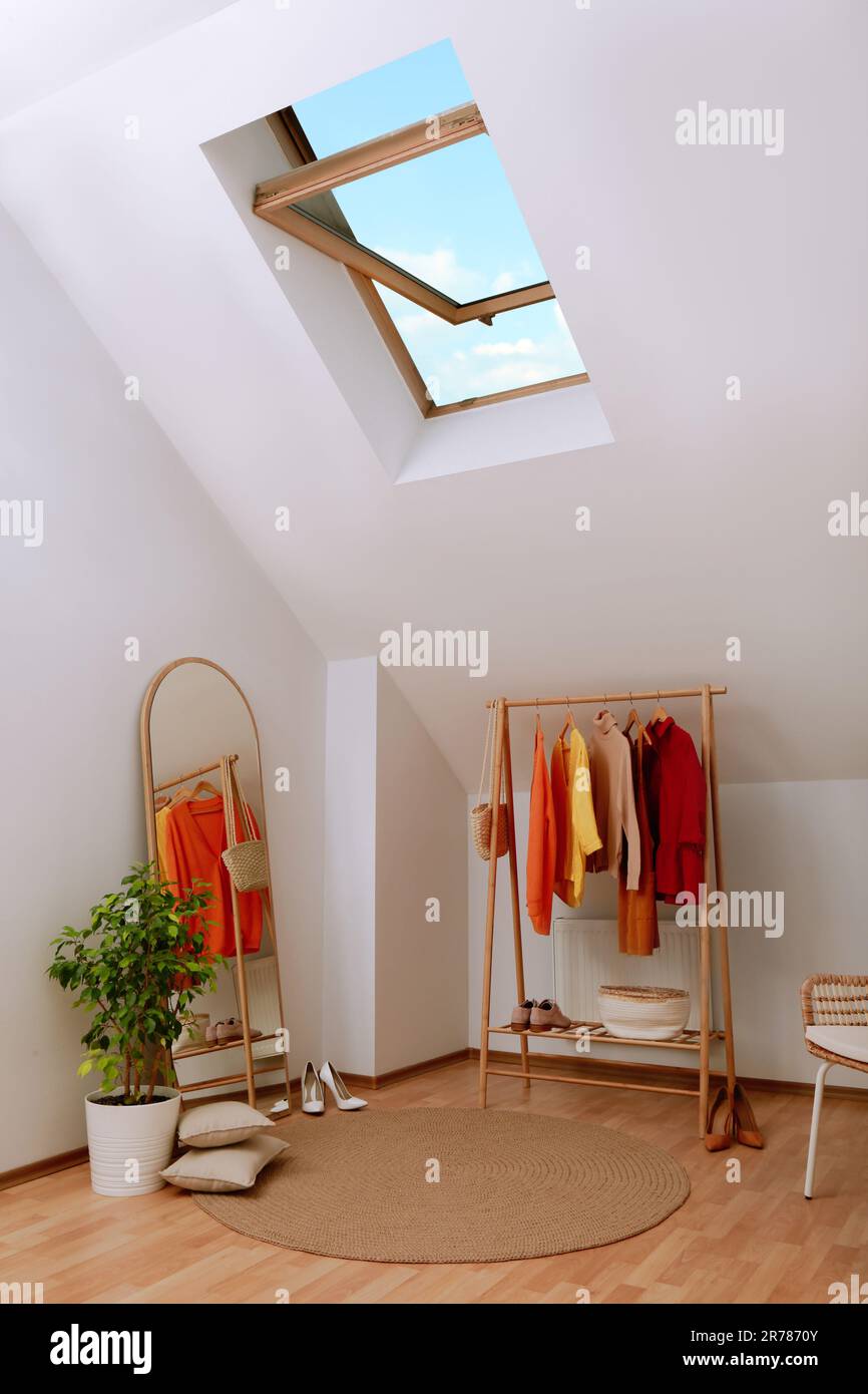 Stylish clothes rack, mirror and wicker chair in attic room. Interior ...