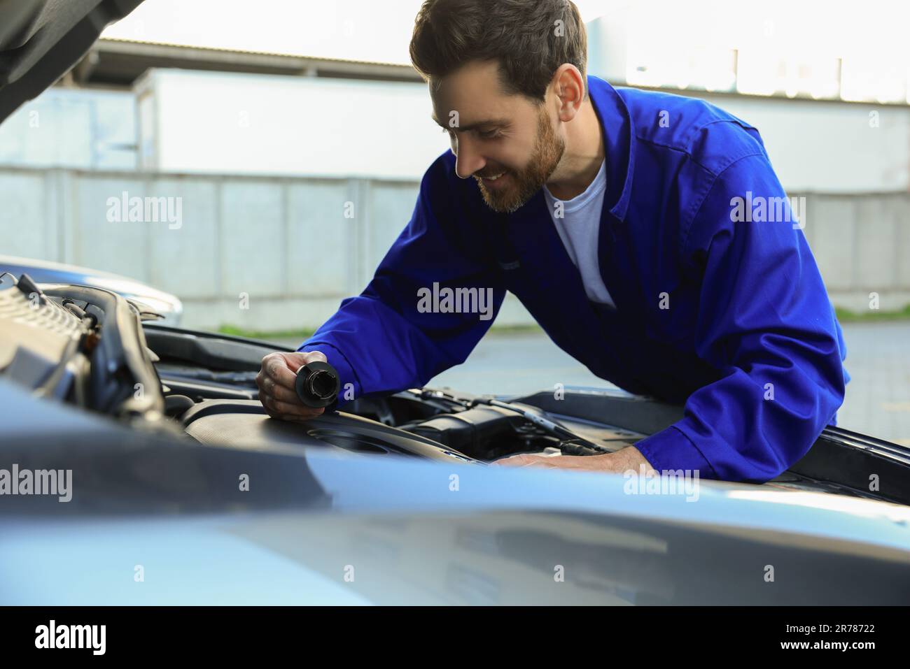 Worker working with modern car engine outdoors Stock Photo - Alamy
