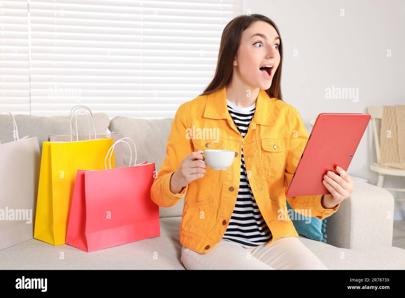 Special Promotion. Emotional woman holding tablet and cup on sofa ...