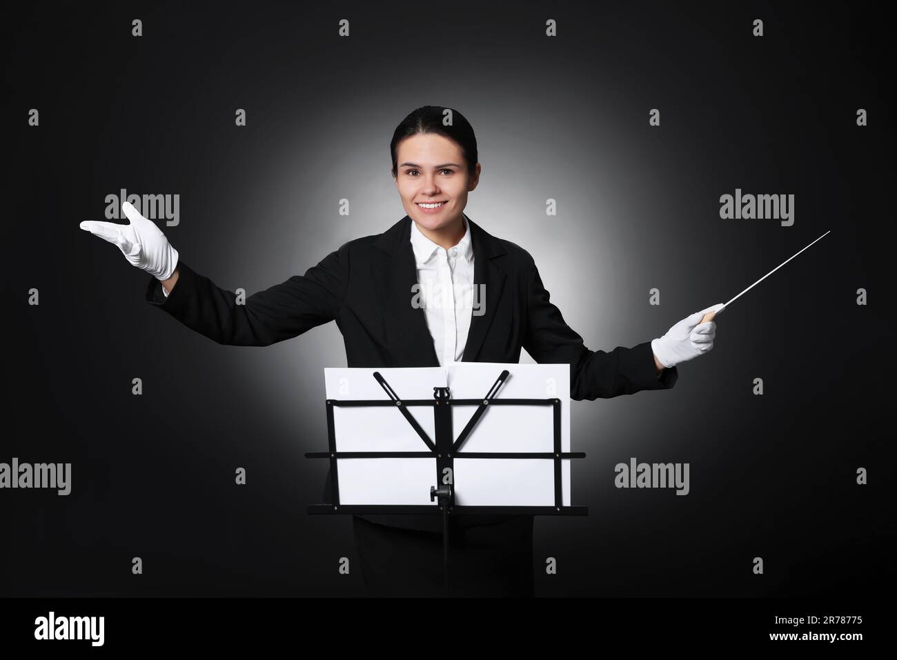 Professional conductor with baton and note stand on black background ...
