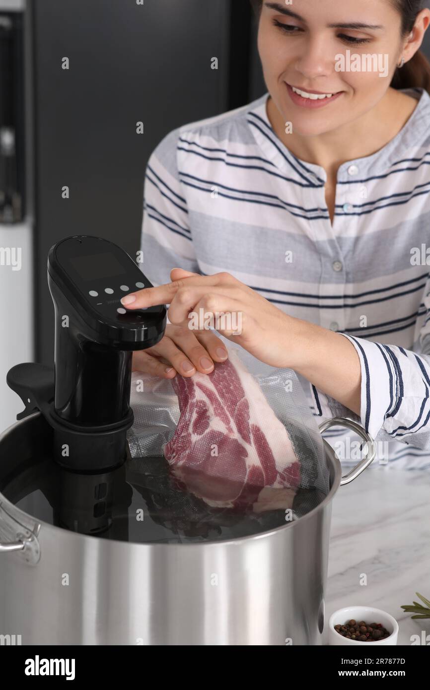 Woman putting vacuum packed meat into pot and using thermal immersion ...