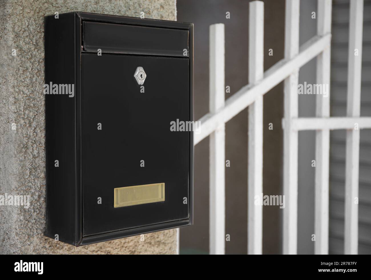 Black metal letter box on beige textured wall, closeup and space for ...