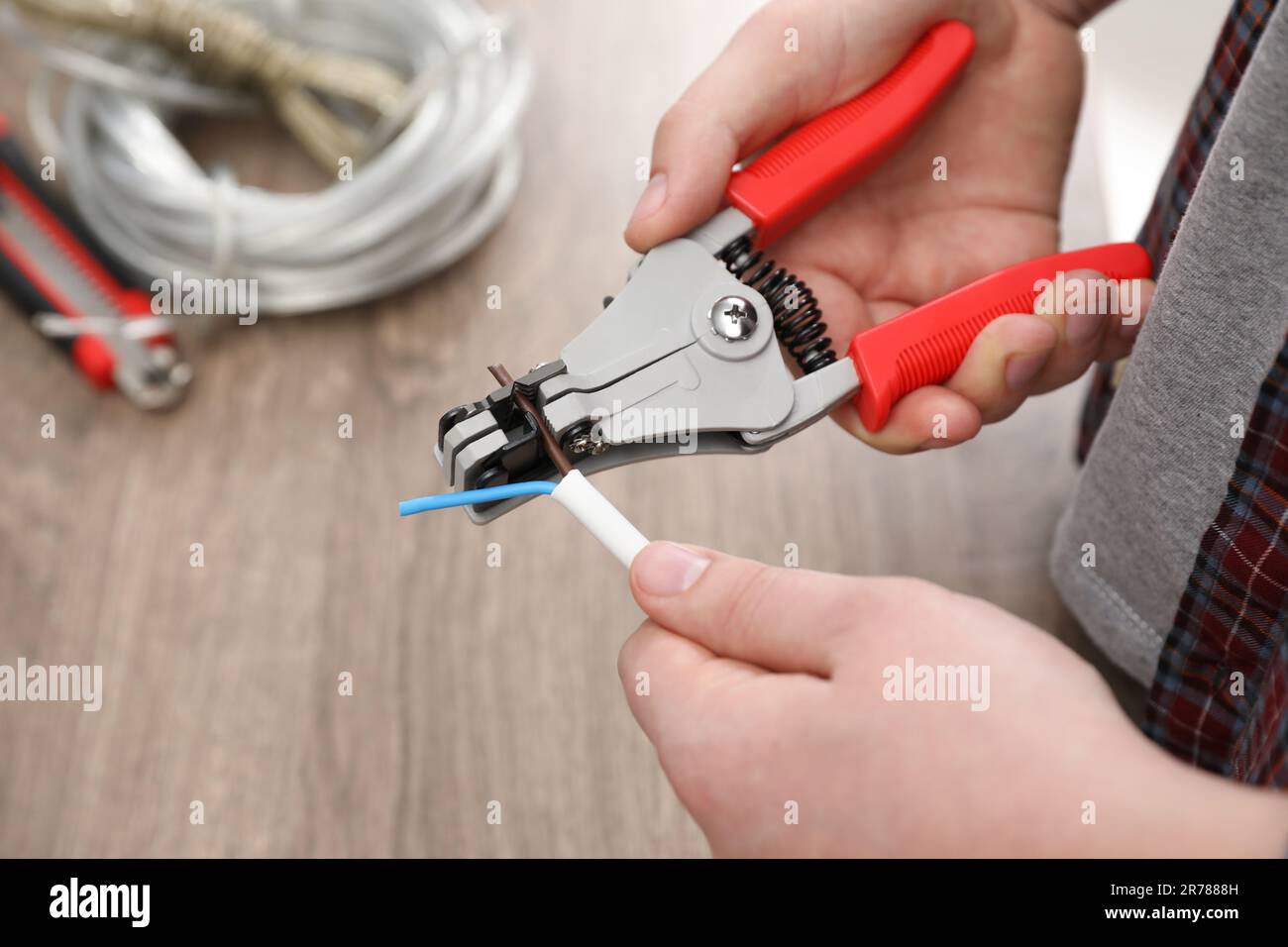 Professional electrician stripping wiring at wooden table, above view ...
