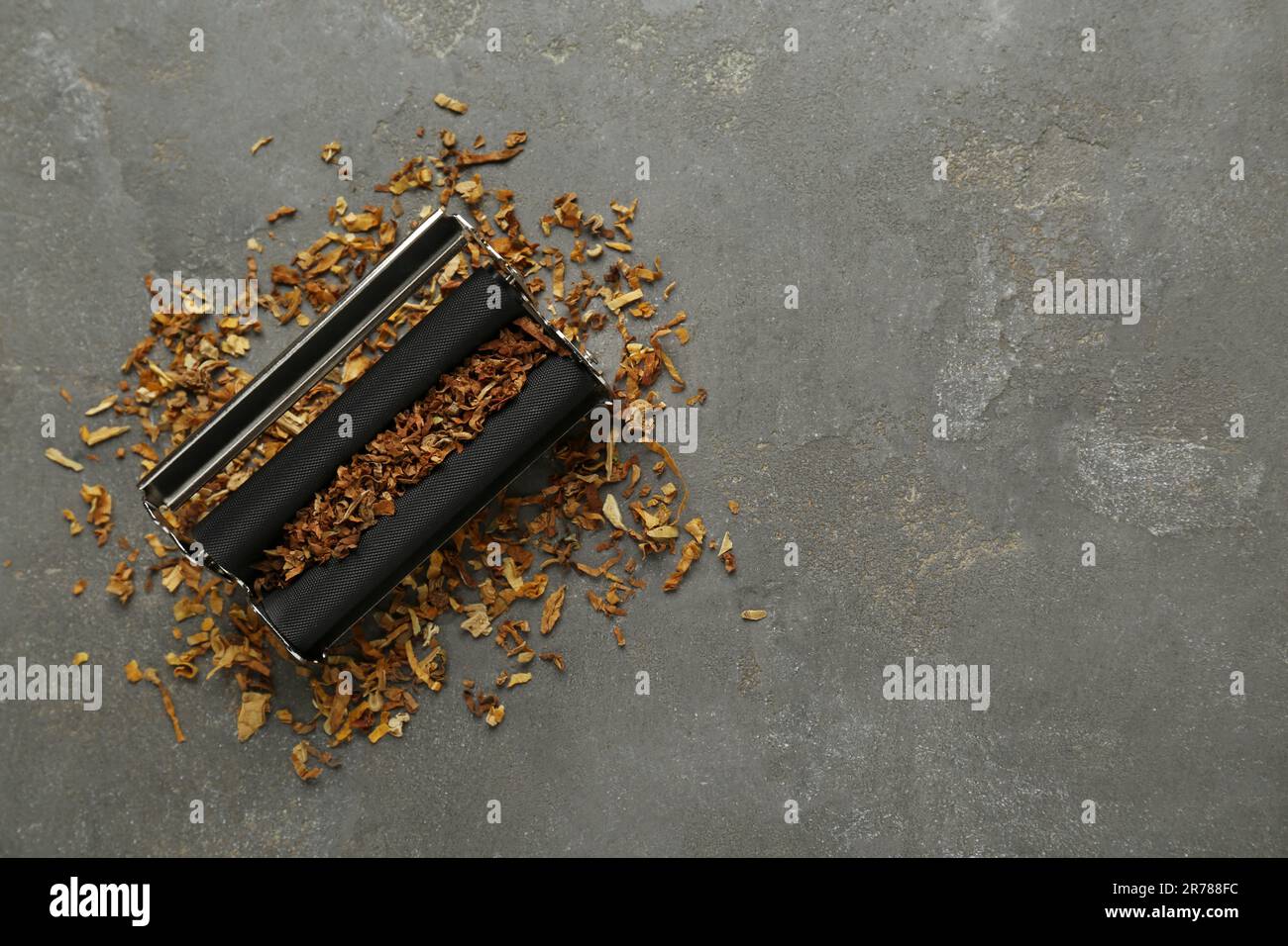 Roller with tobacco on dark grey table, top view and space for text ...