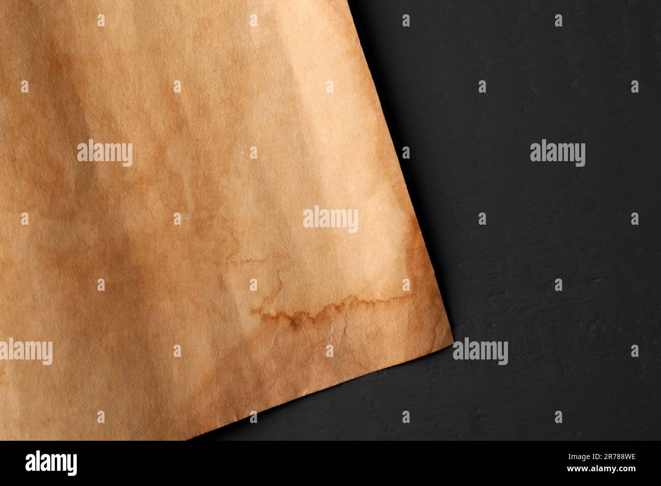 Sheet of old parchment paper on grey wooden table, top view. Space for ...