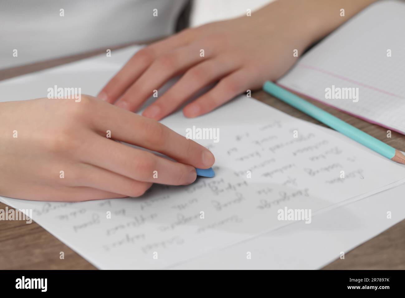 Girl erasing mistake in her notebook at wooden desk, closeup Stock ...