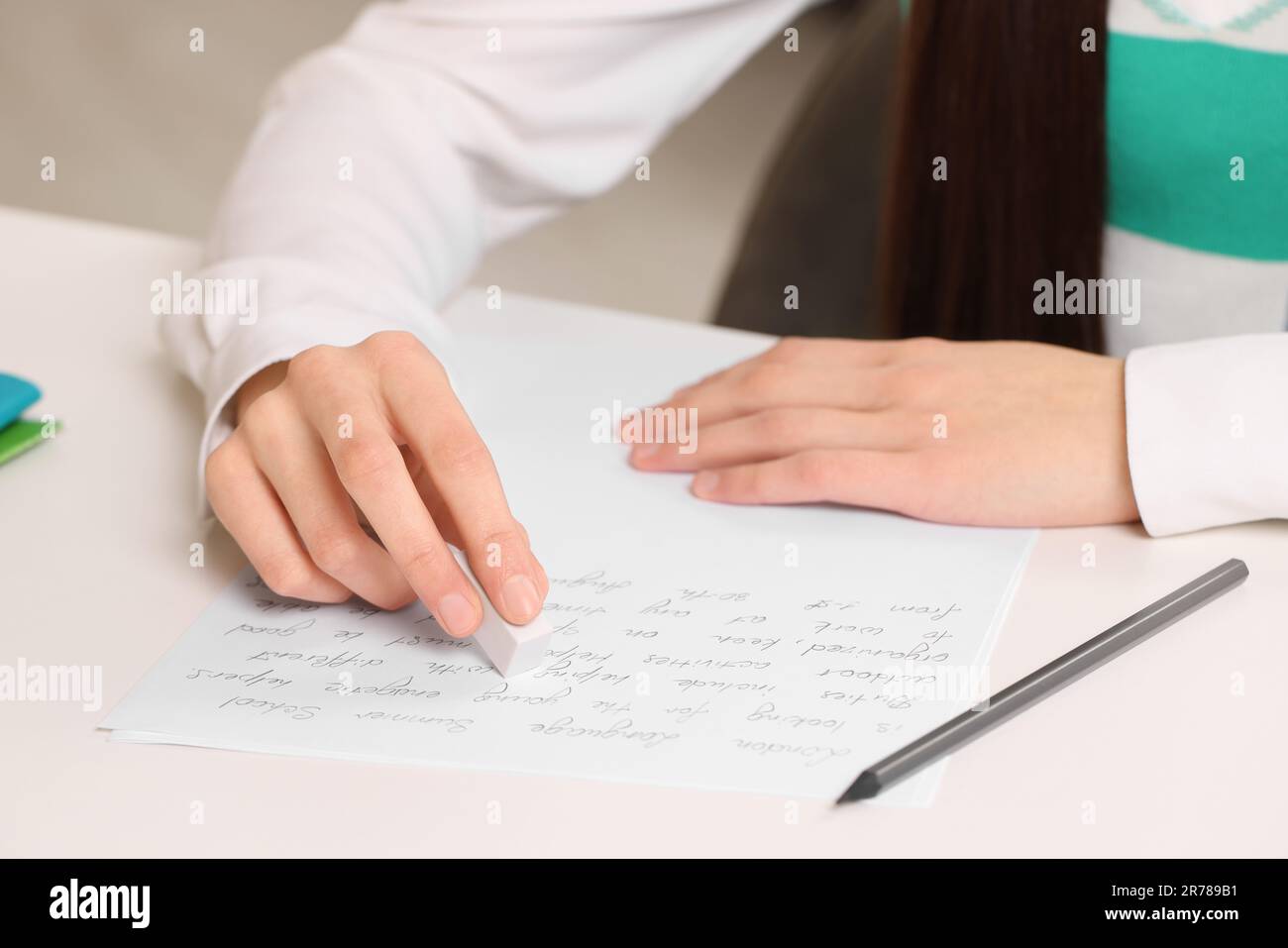 Girl erasing mistake in her notebook at white desk, closeup Stock Photo ...