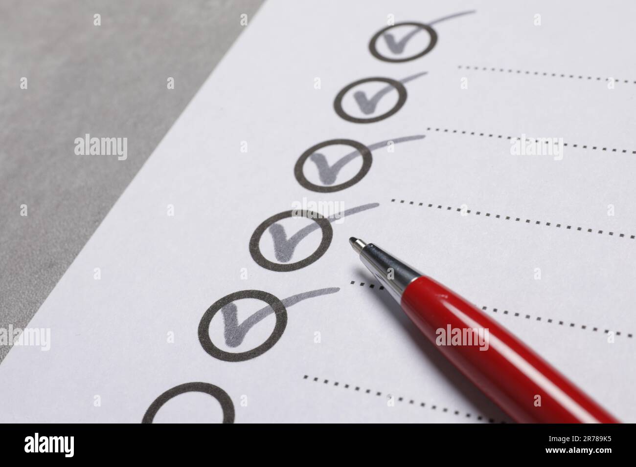 Paper sheet with checkboxes and pen on light grey table, closeup ...