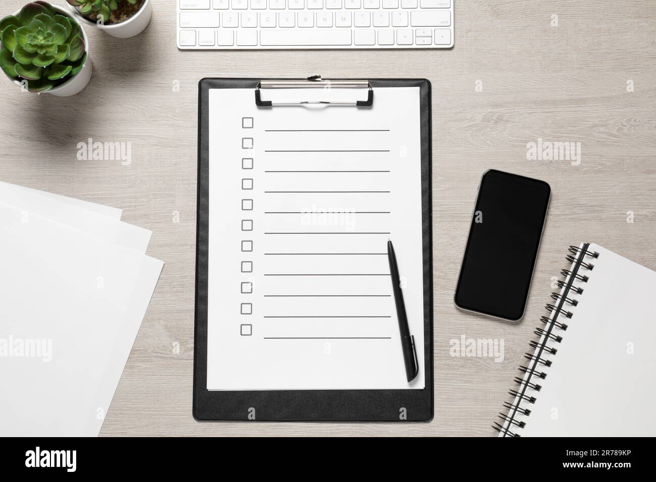 Clipboard with checkboxes, smartphone, plants and computer keyboard on ...