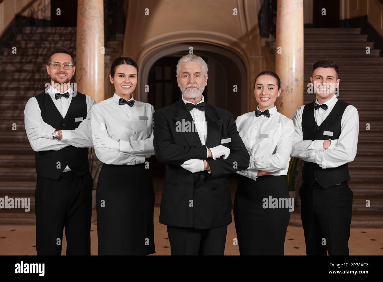 Group of young trainees with teacher in hotel. Professional butler ...