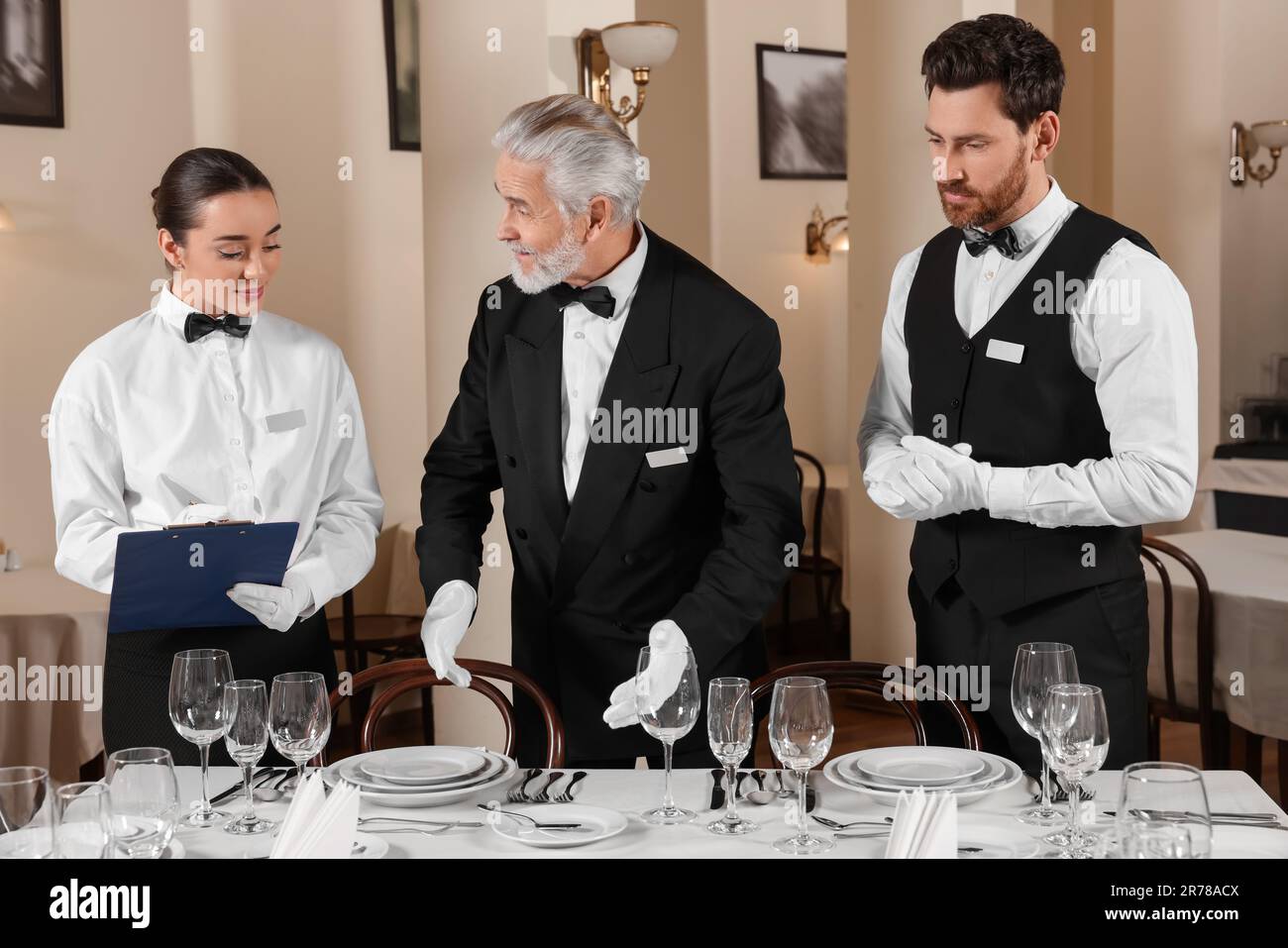Senior man wearing formal suit teaching trainees in restaurant ...