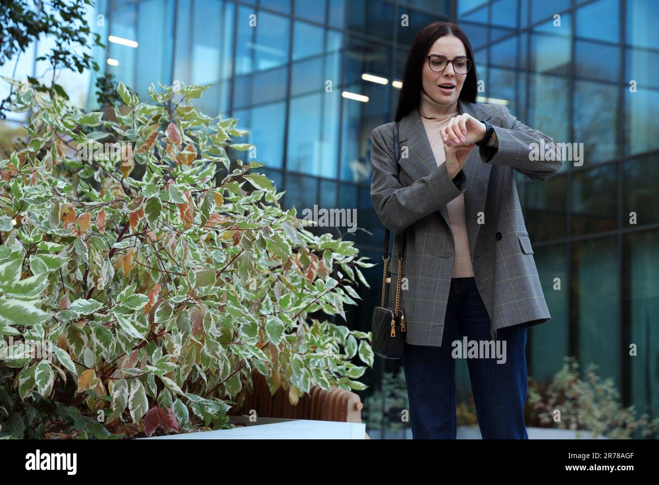 Emotional woman checking time on watch outdoors. Being late concept ...