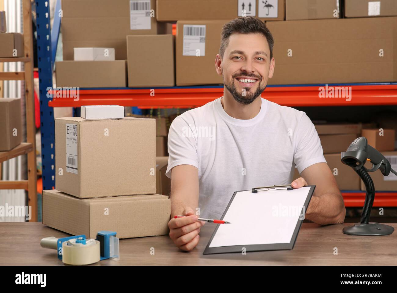 Post office worker with clipboard and parcels at counter indoors Stock ...