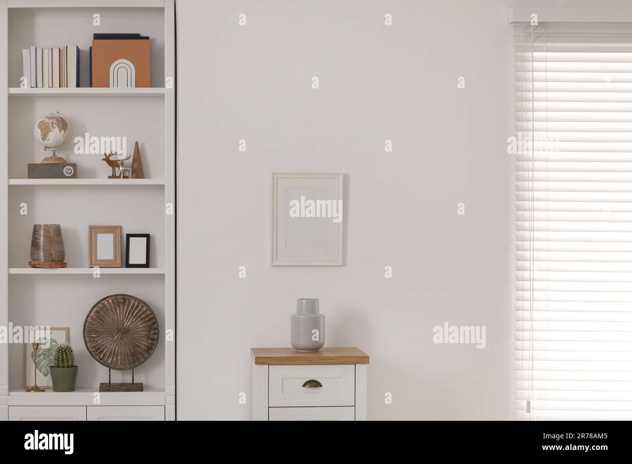 Stylish shelves with different decor elements and chest of drawers in ...