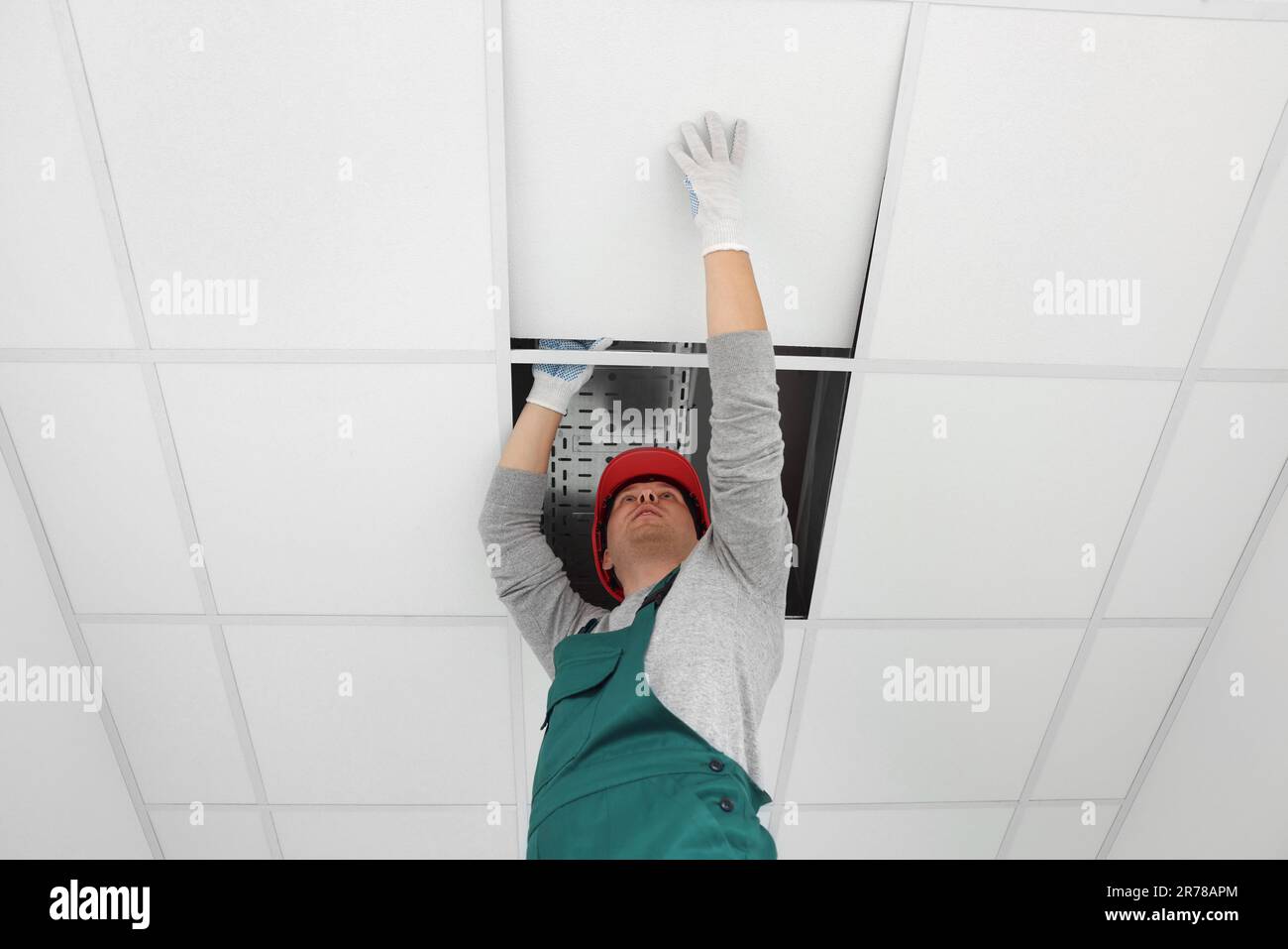 Suspended ceiling installation. Builder working with PVC tile Stock ...