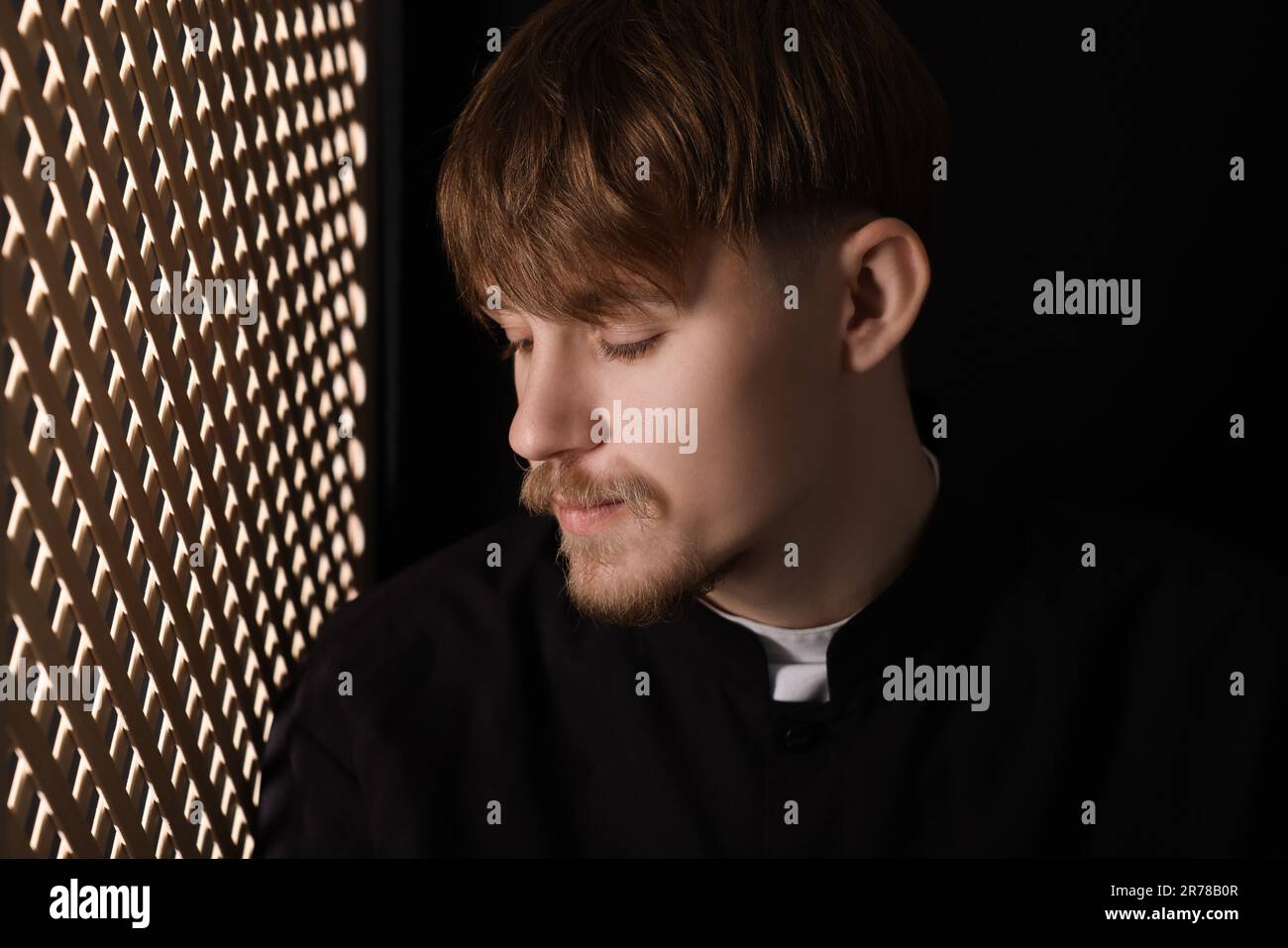 Catholic priest near wooden window in confessional booth Stock Photo ...