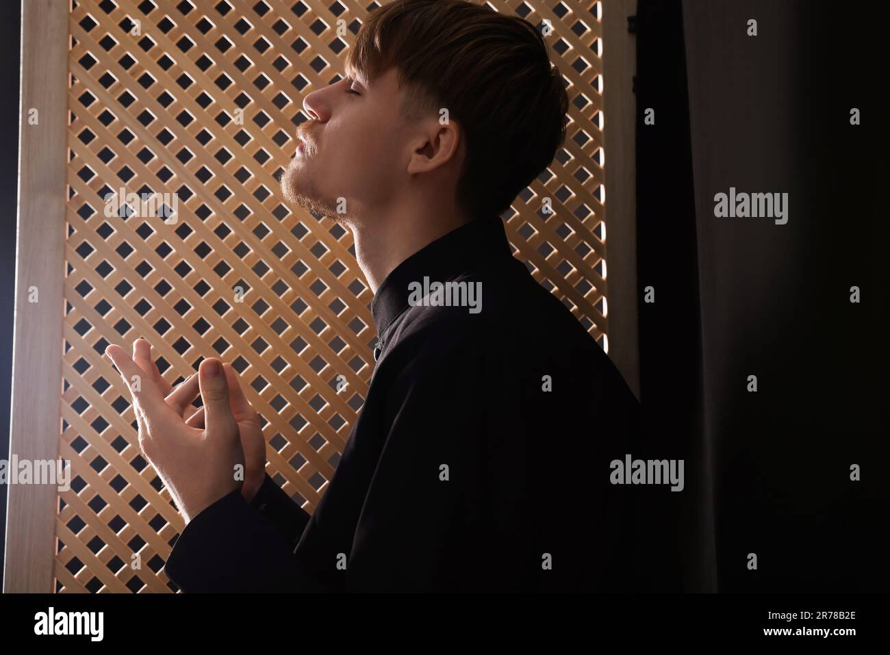 Catholic priest praying near wooden window in confessional booth Stock ...