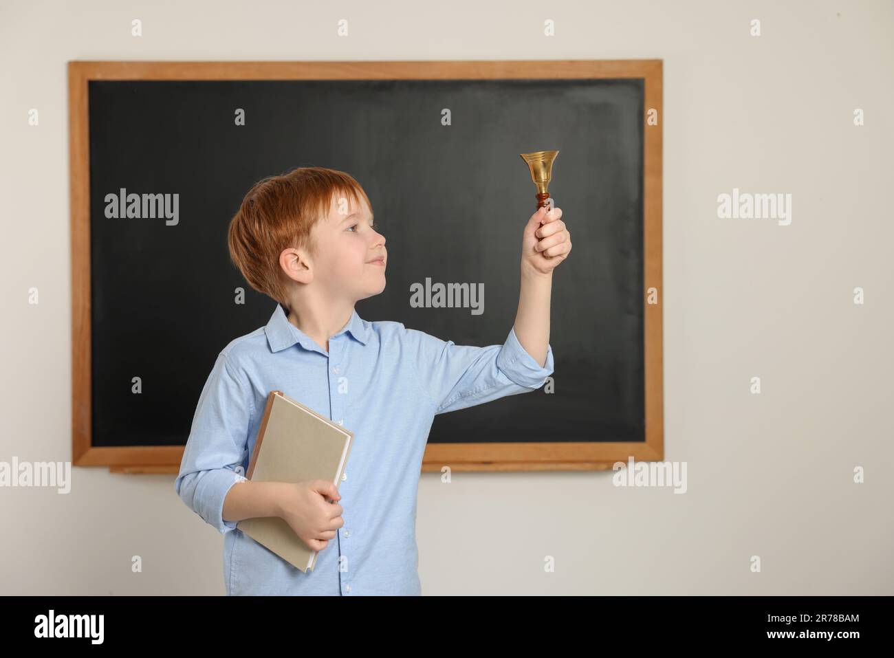 Cute little boy ringing school bell in classroom Stock Photo - Alamy