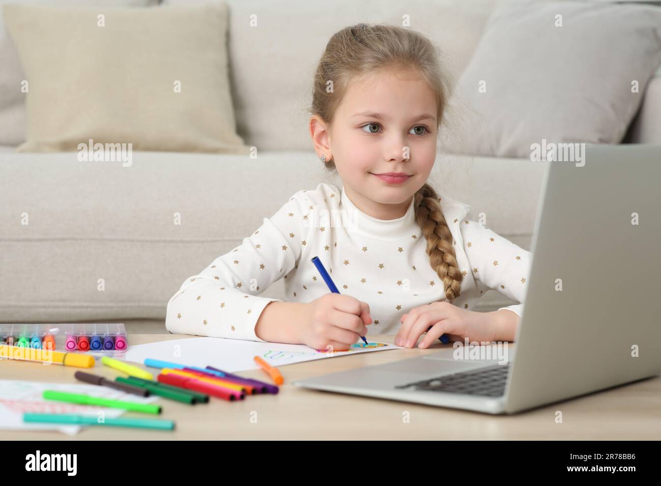Little girl drawing with felt-tip pen following online course at home ...