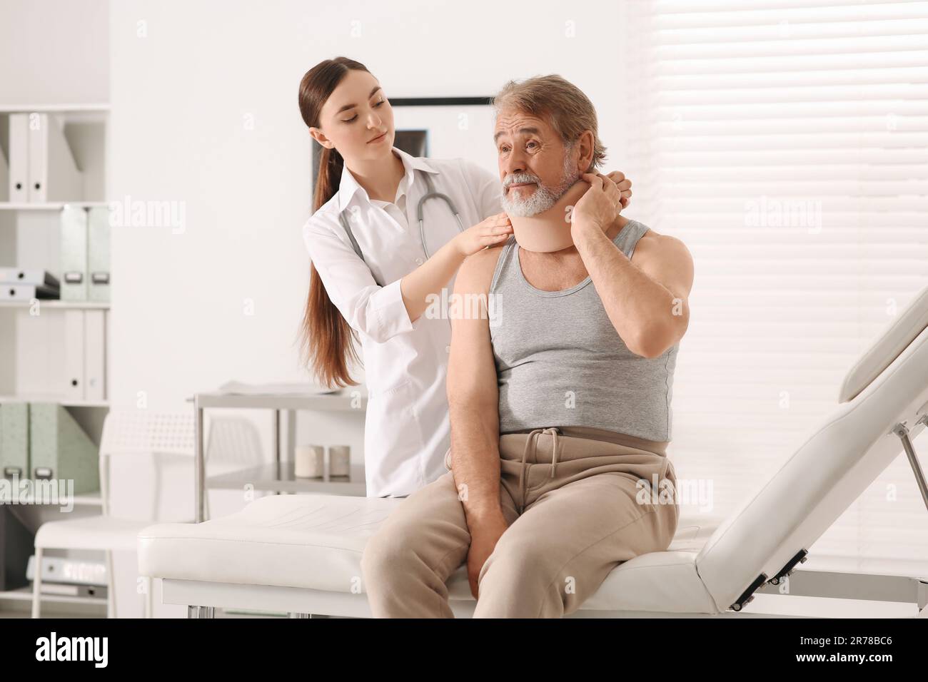 Orthopedist applying cervical collar onto patient's neck in clinic ...