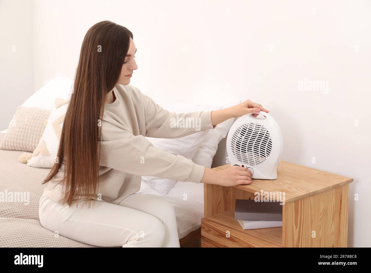 Woman turning on modern electric fan heater at home Stock Photo - Alamy
