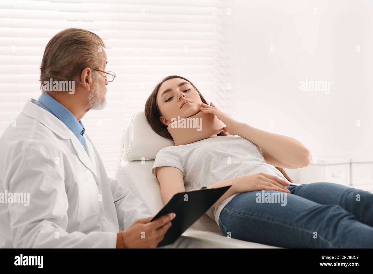 Orthopedist examining patient with injured neck in clinic Stock Photo ...