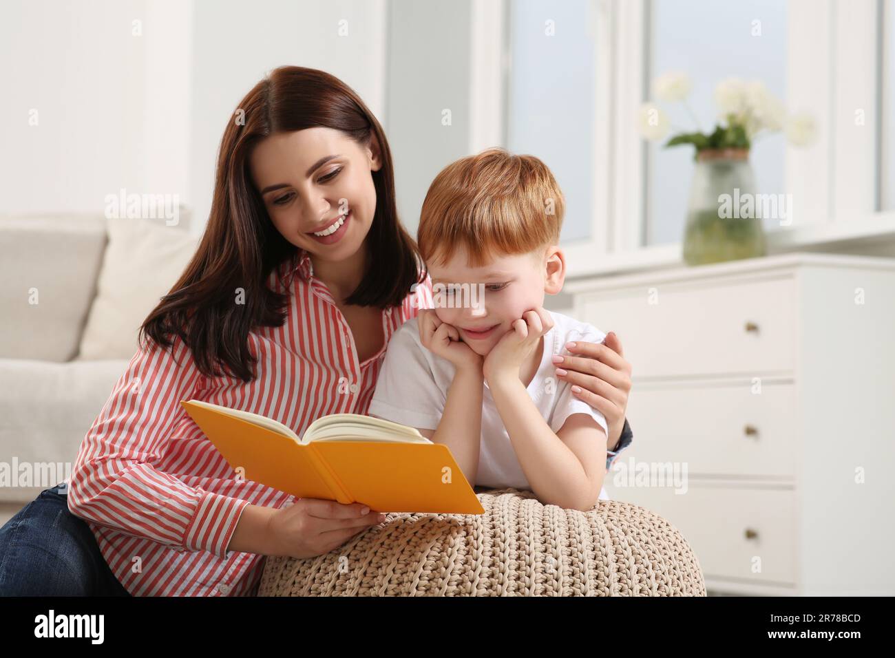 Happy mother reading book with her child at home, space for text Stock ...