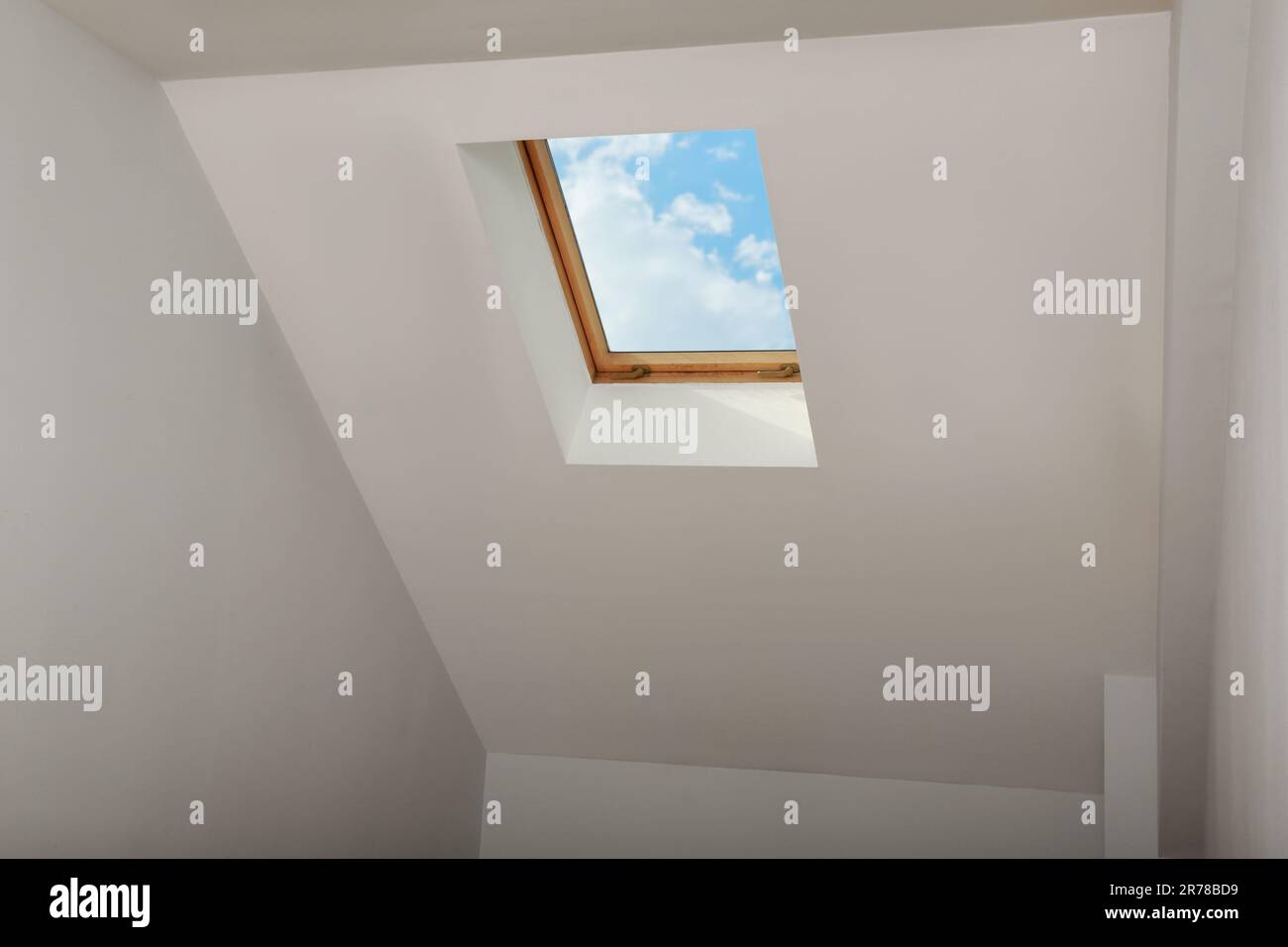 Skylight roof window and lamps on slanted ceiling in attic room, low ...