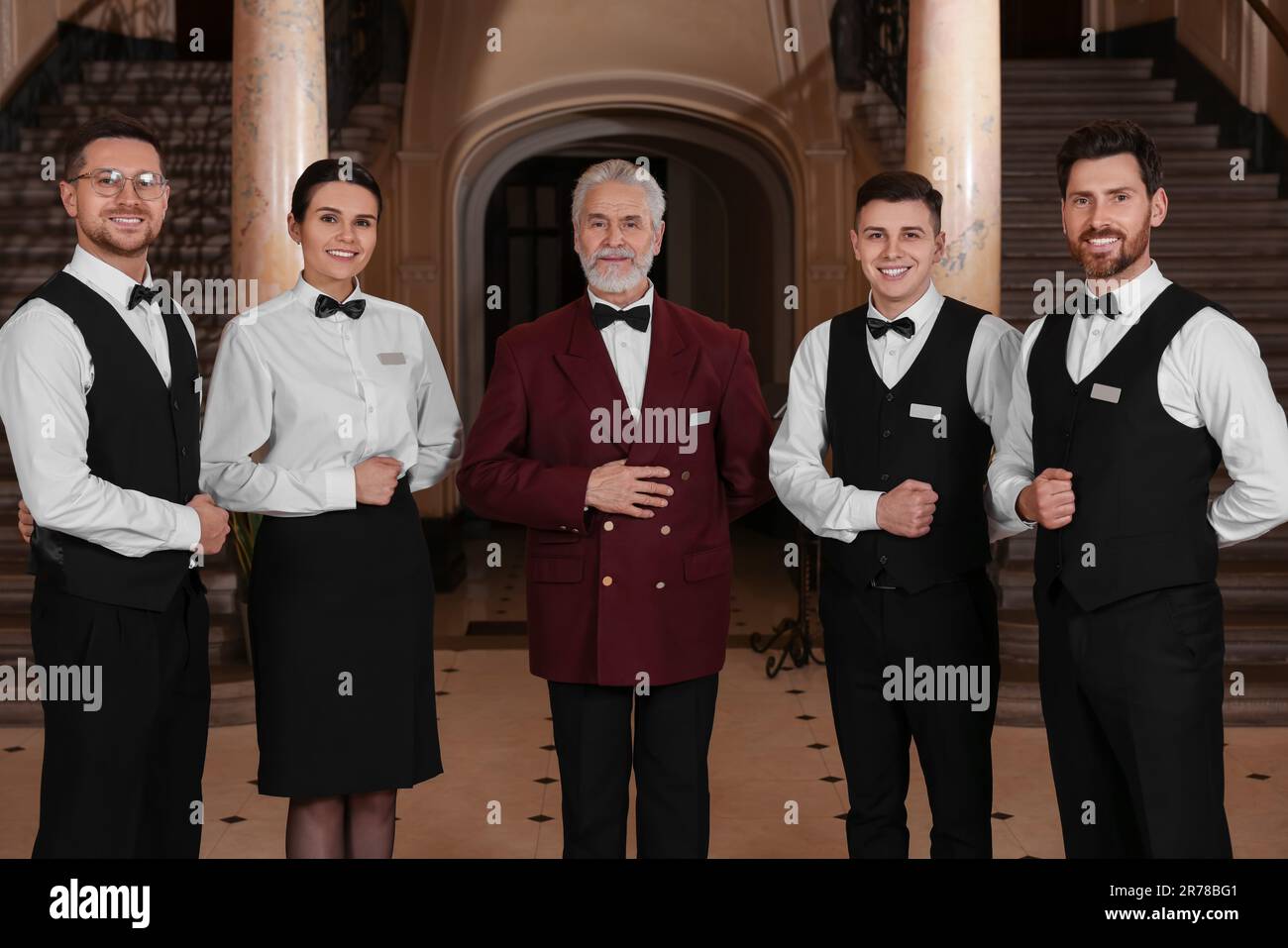 Group of young trainees with teacher in hotel. Professional butler ...